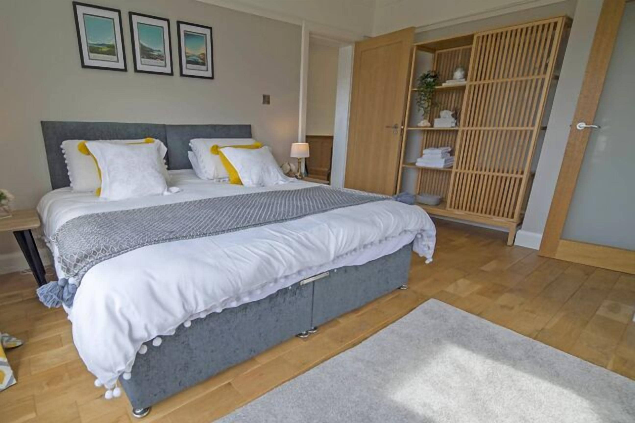 Quarto com cama, guarda-roupa de madeira e mesa de cabeceira.