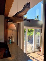 Quarto com teto de madeira, uma luminária, uma garrafa de água e porta de vidro que dá para o exterior.