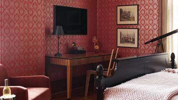 Um quarto com cama, escrivaninha, cadeira, televisão e piano.