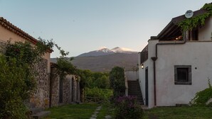 Um pátio com uma montanha ao fundo, degraus de pedra e vegetação.
