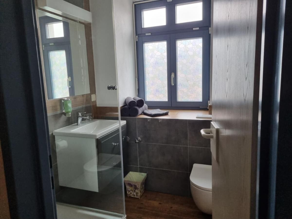 Casa de banho compacta com sanita, lavatório e chuveiro.