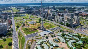 Paisagem urbana com uma torre imponente, um cruzamento rotatório central e vegetação ao redor.