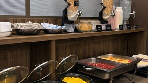 Buffet com diversas opções de comida, incluindo saladas, pratos quentes e uma área de bebidas.