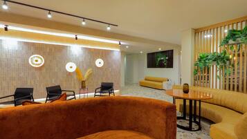 Um hall de hotel moderno com área de estar, balcão de recepção e parede decorativa com luminárias circulares.