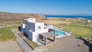 Uma villa moderna e branca, com piscina e vista para o mar.