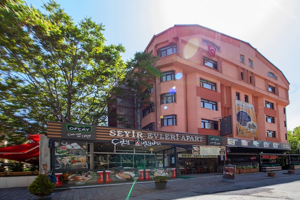Um edifício de vários andares com um restaurante chamado "SEYIR EVLERIAPART" no andar térreo.