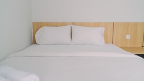 Cama bem arrumada com lençóis brancos e cabeceira de madeira.