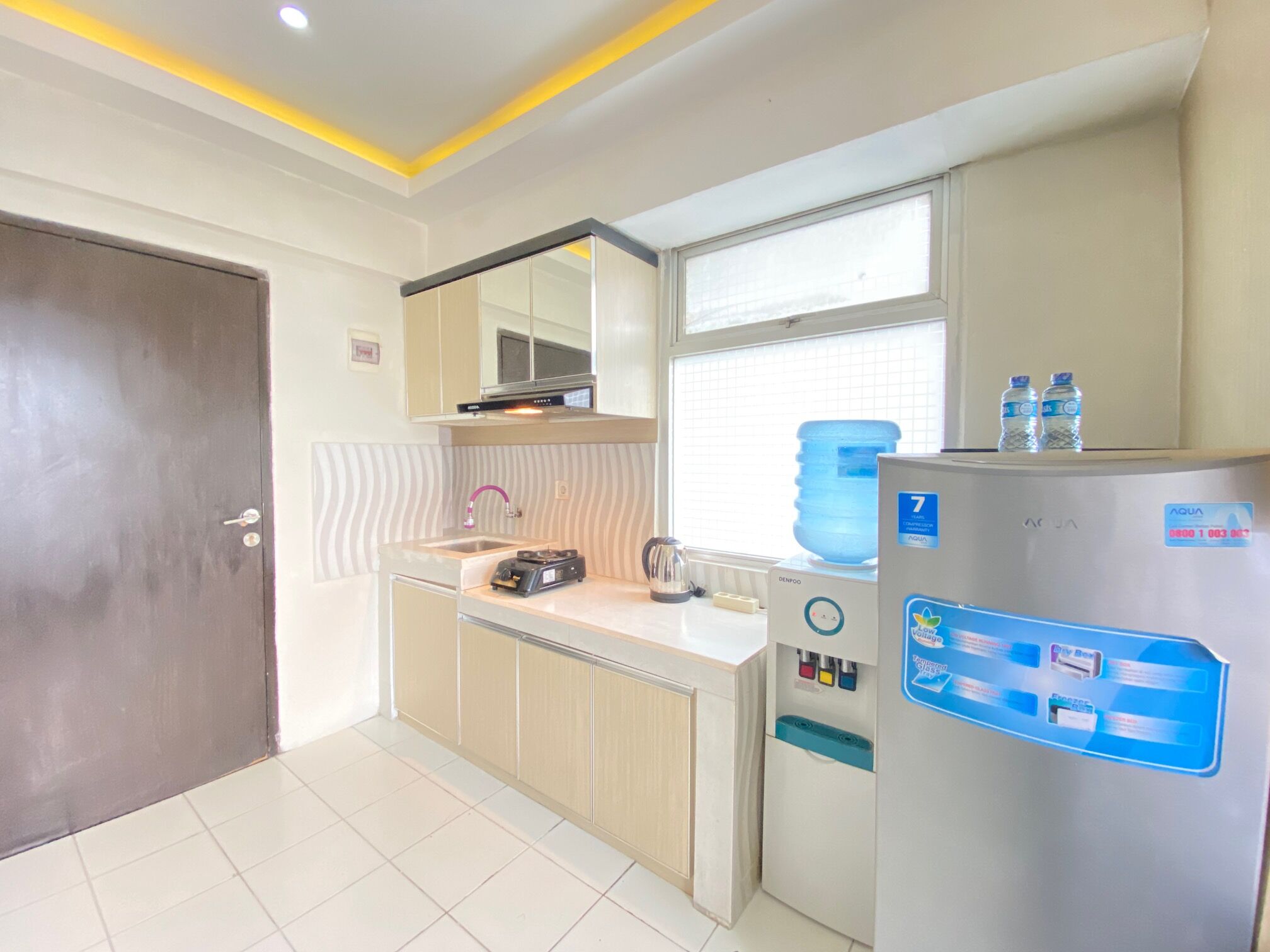 Cozinha compacta com geladeira, bebedouro e micro-ondas.