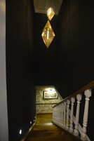 Uma escadaria com corrimão de madeira e balaústres brancos, que leva a um patamar com uma moldura e um quadro na parede.
