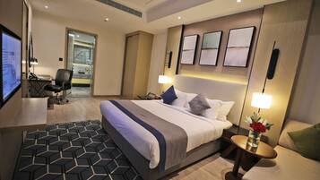 Quarto de hotel moderno com uma cama grande, mesas de cabeceira, escrivaninha e televisão.