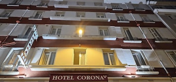 Um hotel de vários andares com varandas e uma placa com a inscrição 'HOTEL CORONA'.