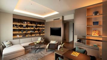 Uma sala de estar moderna com sofá seccional, mesa de centro, TV e estantes embutidas com objetos decorativos.