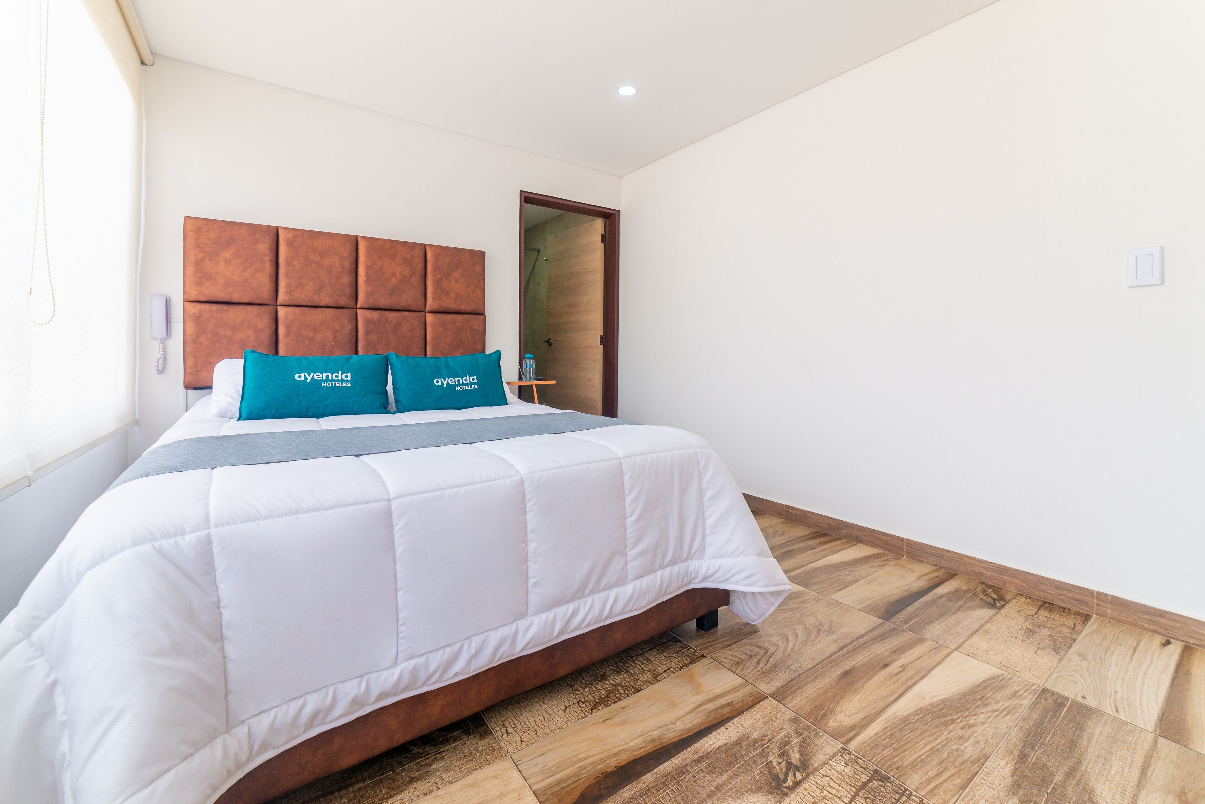 Quarto de hotel com uma cama grande, cabeceira de madeira e piso de madeira.