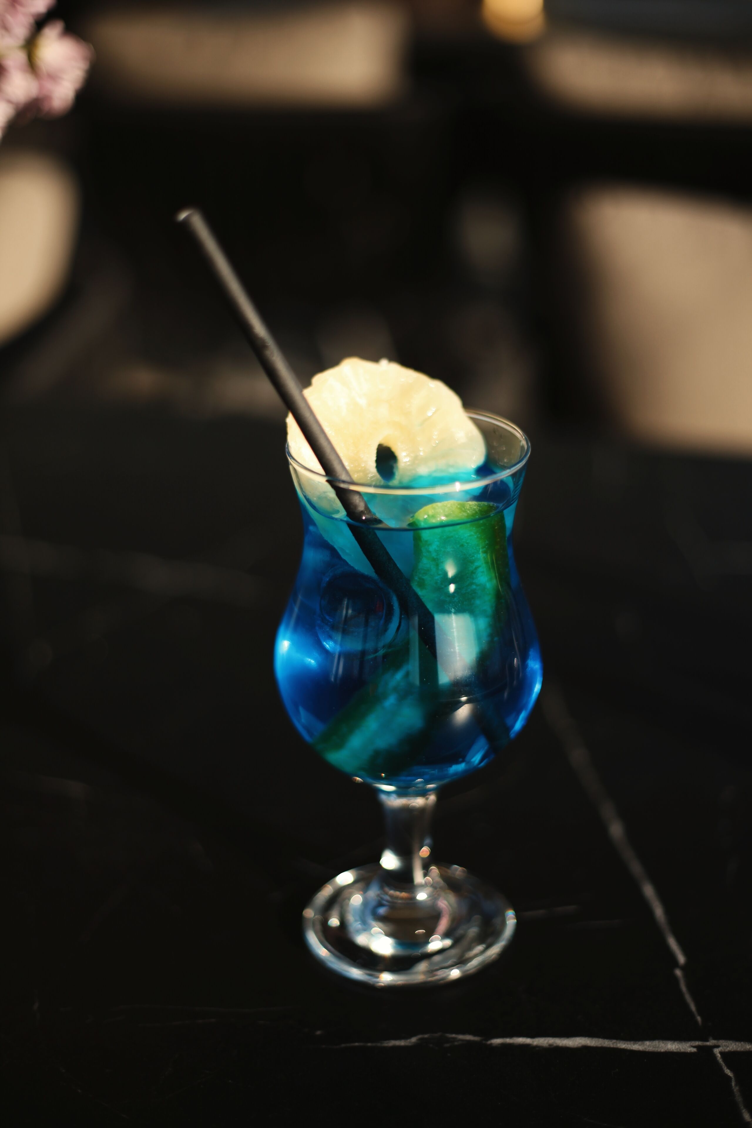 Um cocktail num copo, com canudo, gelo e uma rodela de limão.