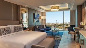 Quarto de hotel moderno com uma cama grande, um sofá, uma escrivaninha e vista para a cidade.