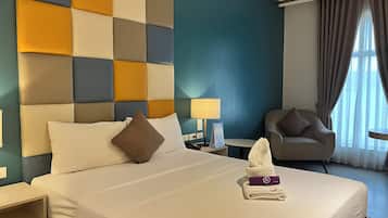 Quarto de hotel com uma cama, mesa de cabeceira, cadeira, luminária e janela com cortinas.