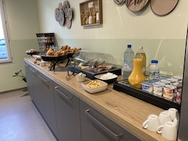 Um buffet de café da manhã com pães, queijos e bebidas.