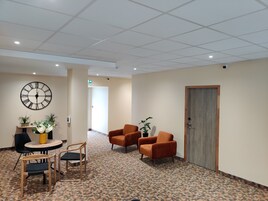 Um hall com relógio, área de estar e uma porta.