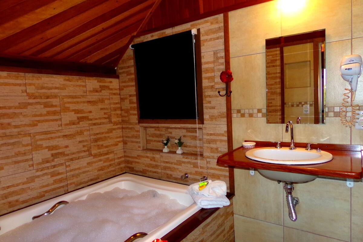 Casa de banho com banheira, pia, espelho e porta-toalhas.