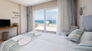 Quarto de hotel com duas camas, televisão e vista para a praia.