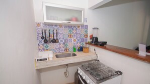 Uma cozinha compacta com fogão a gás, pia e janela sobre o balcão.
