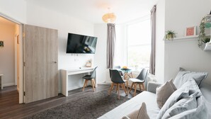 Um quarto moderno com cama, escrivaninha e televisão.