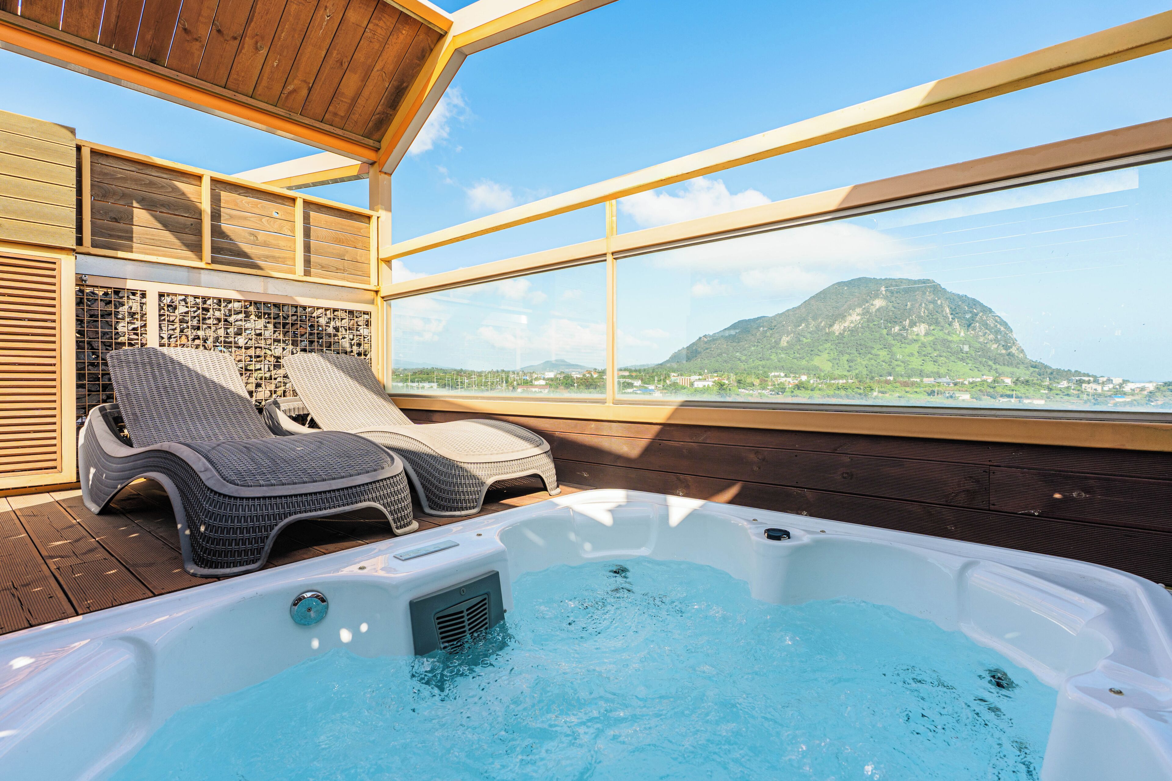 Uma banheira de hidromassagem com duas cadeiras de descanso em um deck de madeira, com vista para uma paisagem montanhosa.