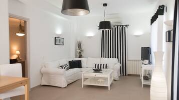 Uma sala de estar moderna com um sofá branco, uma mesa de centro e uma luminária pendente preta.