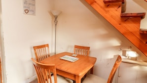 Uma área de refeições com uma mesa de madeira e quatro cadeiras, um abajur e uma placa na parede.