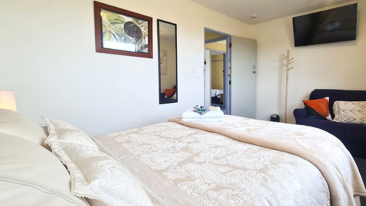Quarto com cama, sofá, televisão e espelho.