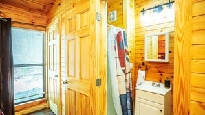 Interior de uma cabana de madeira com banheiro, incluindo pia, espelho e porta-toalhas.