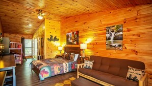 Interior de cabana com cama, sofá e área de jantar.