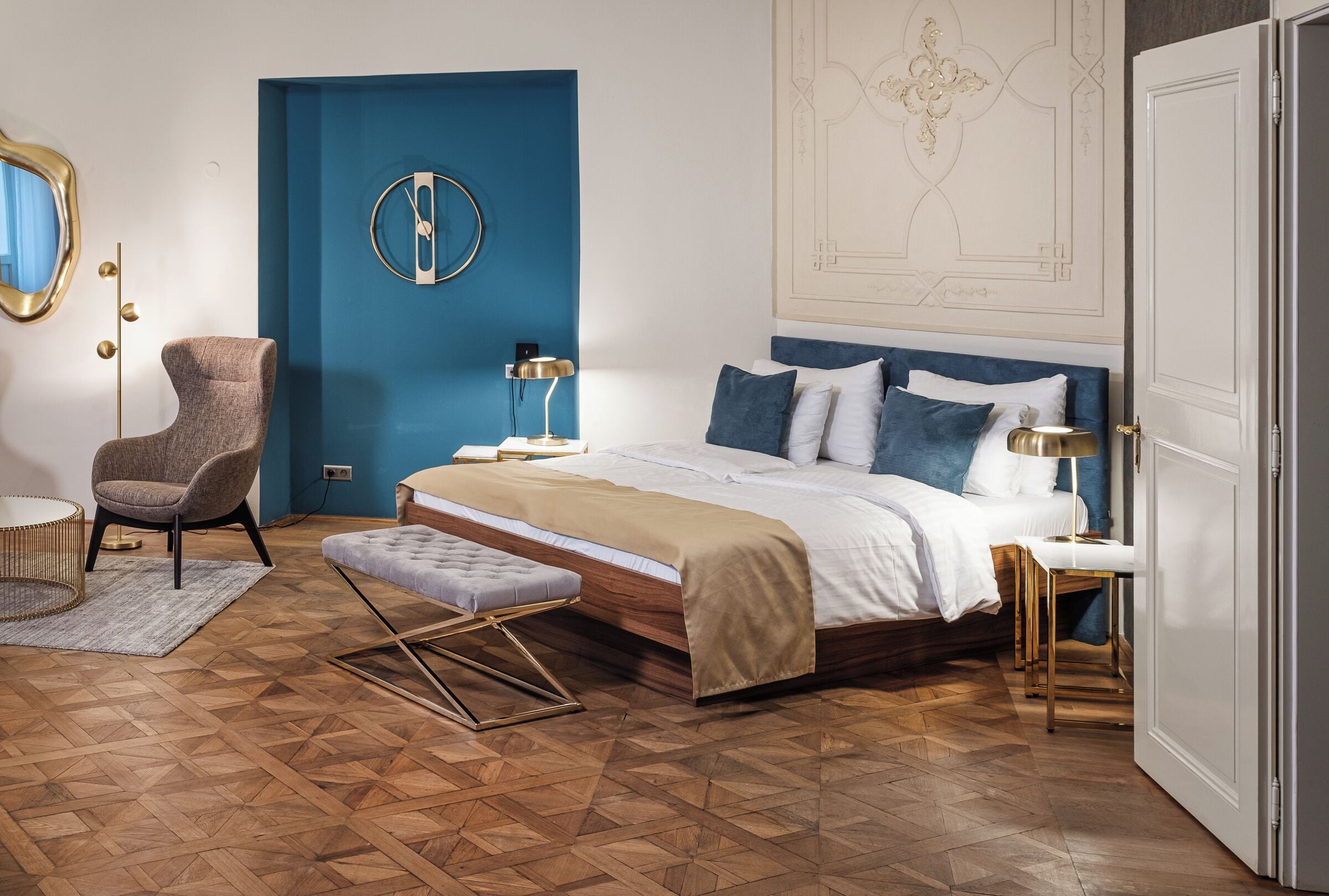 Quarto com cama grande, uma cadeira, uma mesinha e espelho fixado na parede.