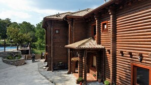 Uma cabana de toras com um pátio de pedra, área de estar externa e vista para um lago.