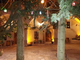 Um edifício tradicional com pátio, soalho de pedra e vasos de plantas.