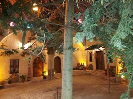 Um pátio interno com piso de pedra, portas em arco e plantas em vasos.