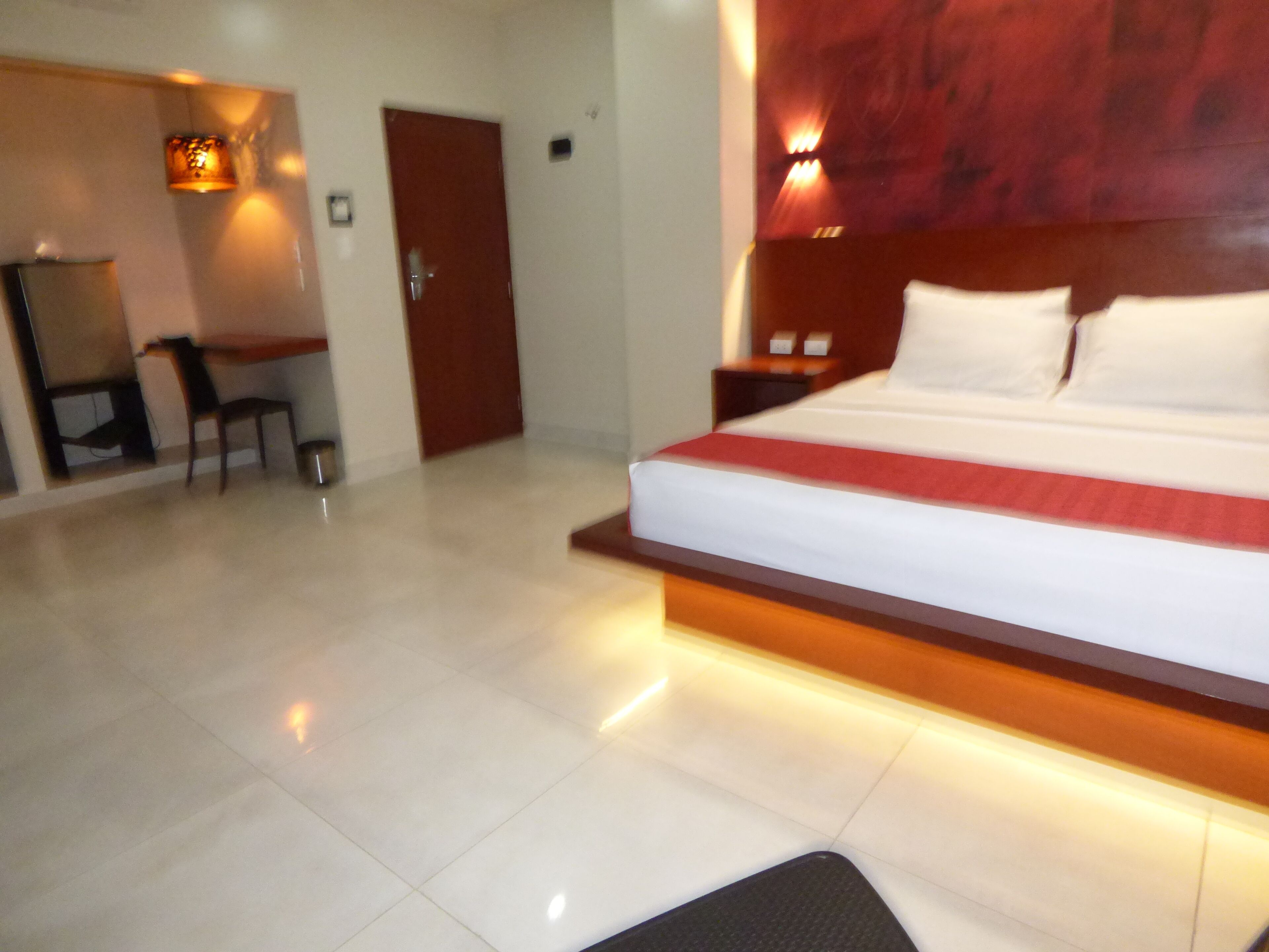Quarto de hotel com uma cama grande, uma escrivaninha e uma cadeira.