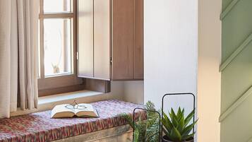 Quarto com janela, estante e planta em vaso.