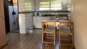 Uma cozinha compacta com armários brancos, micro-ondas, pia e janela.