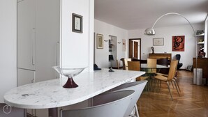Cozinha moderna com bancada de mármore, área de jantar com cadeiras de madeira e um espelho grande.