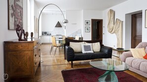 Uma sala de estar moderna com um sofá de couro preto, uma mesa de centro de vidro e um armário de madeira.