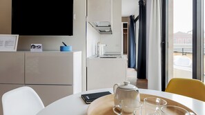 Uma cozinha moderna com televisão de tela plana, cafeteira e área de jantar com mesa e cadeiras.