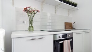 Uma cozinha moderna com armários brancos, forno embutido e bancada com um vaso de flores.