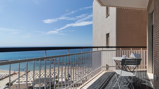 Uma varanda com vista para a praia e o mar.