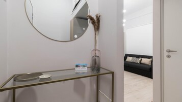 Um banheiro moderno com toucador de vidro, espelho redondo e placa de 'Proibido Fumar'.