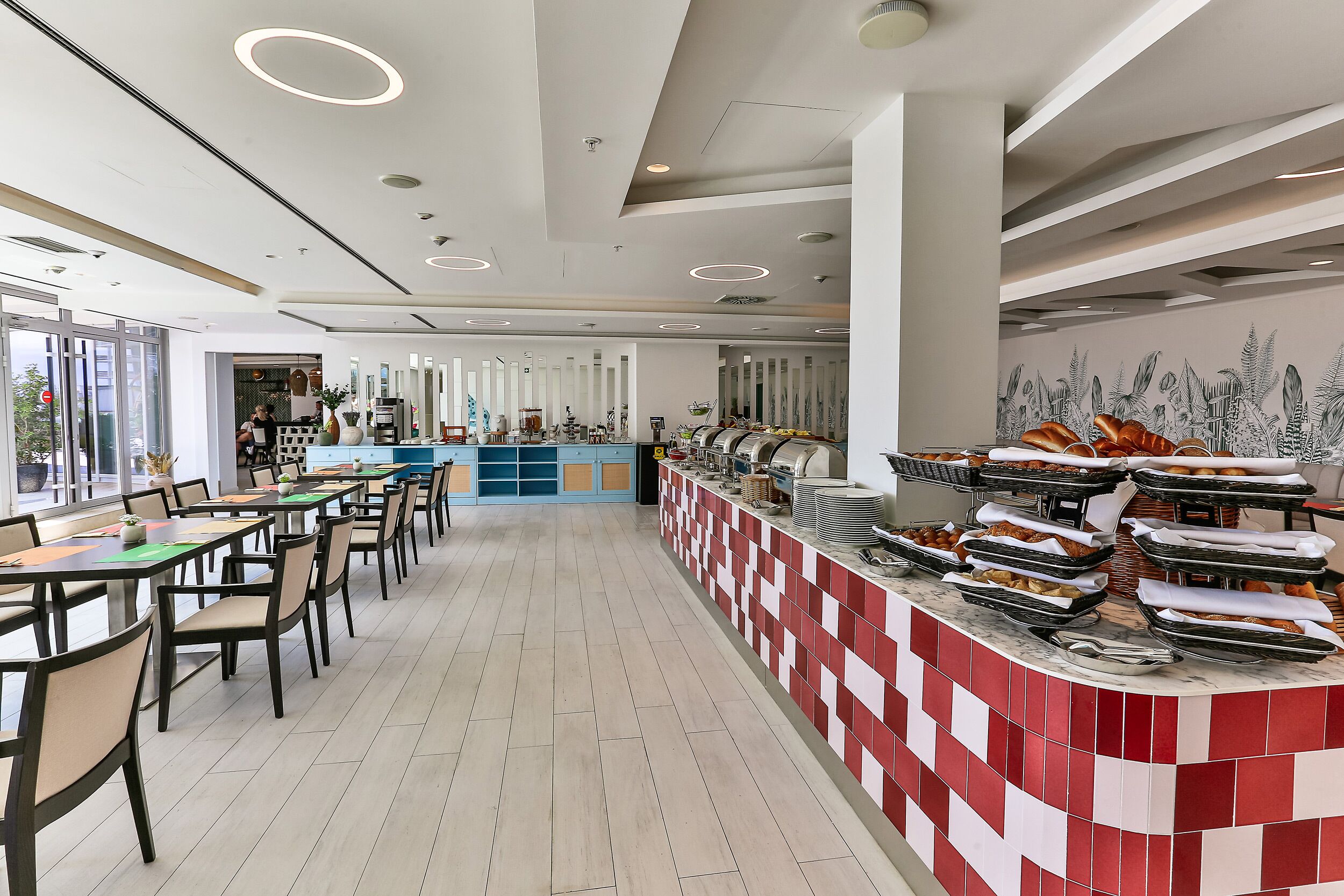 Um restaurante moderno com área de buffet, mesas compridas e cadeiras.