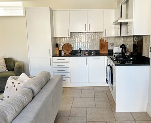 Uma cozinha moderna com armários brancos, uma ilha central e fogão embutido.