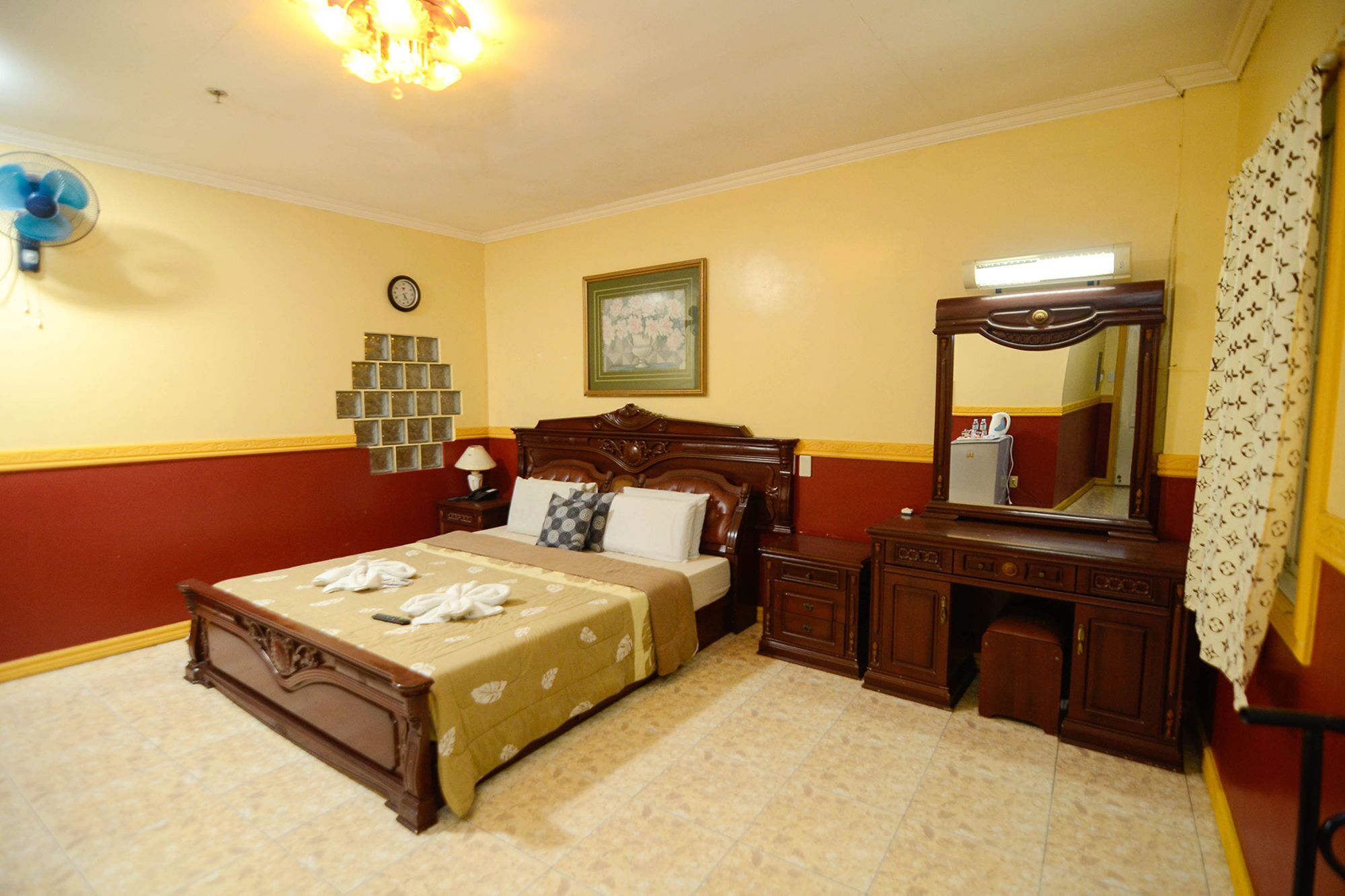 Quarto com cama, mesa de cabeceira, cômoda, espelho, relógio e decoração na parede.