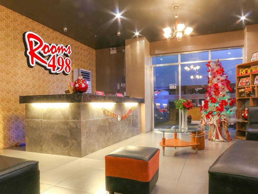 Um saguão de hotel com uma mesa de recepção, um pinheiro de Natal e áreas de estar.