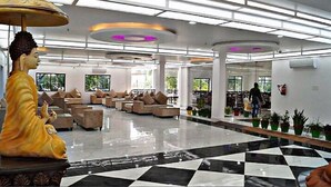 Um lobby moderno com uma estátua de Buda, áreas de estar e um extintor de incêndio na parede.